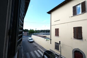 Vista da rua com um edifício à direita, um carro branco estacionado em frente e uma faixa de pedestres.