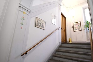 Uma escada com corrimão, uma porta na base e duas imagens emolduradas na parede.