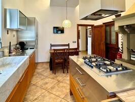 Uma cozinha moderna com fogão a gás, cadeiras de madeira e uma mesa de jantar.