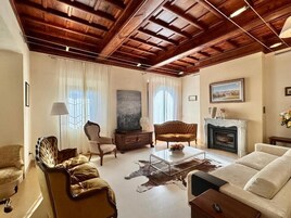 Uma sala de estar com lareira, sofás de couro, uma mesa de centro e um quadro grande.