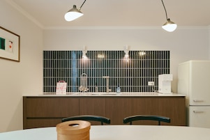 Cozinha moderna com painel de azulejos pretos, geladeira branca e área de jantar com duas cadeiras.