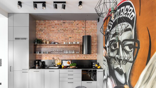 A modern kitchen with a brick wall, stainless steel appliances, and a mural.