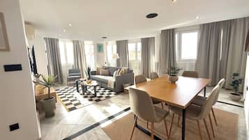 Uma sala de estar moderna com sofá, mesa de centro e mesa de jantar.