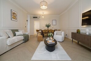 Uma sala de estar moderna com um sofá, uma mesa de centro e uma área de jantar com cadeiras.