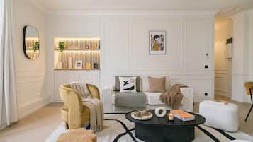 Uma sala de estar moderna com sofá, poltrona, mesa de centro e uma estante decorativa.