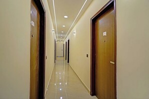 Corredor de hotel com portas de madeira, placas com números e iluminação embutida.