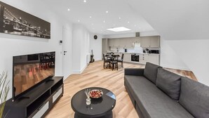 Uma sala de estar moderna com televisão de tela plana, uma mesa de centro preta e um sofá cinza.