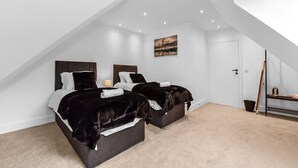 Quarto com duas camas, um quadro, uma porta e uma escada.