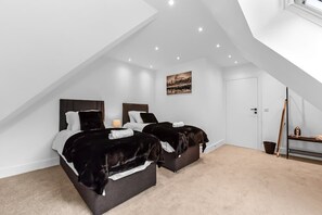 Quarto com duas camas, um quadro, uma porta e uma escada.