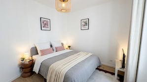 Quarto com cama, mesas de cabeceira, abajur e quadros na parede.