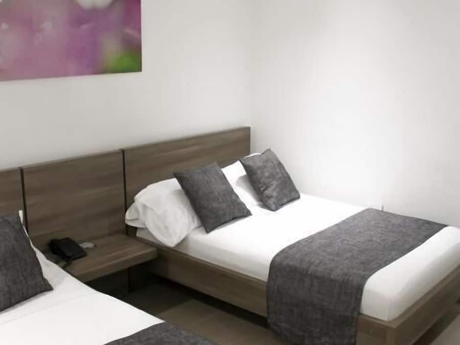 Quarto de hotel moderno com duas camas, uma mesa de cabeceira e um quadro pendurado na parede.