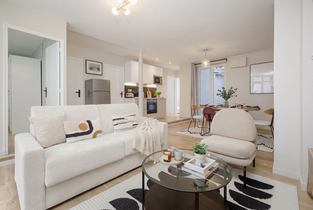 Uma sala de estar moderna com sofá, mesa de centro e um espaço de jantar com cadeiras.