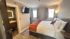 Quarto de hotel com cama, televisão, banheiro e janela.