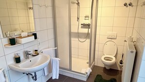 Uma casa de banho moderna com chuveiro em cabine de vidro, pia branca e sanita.