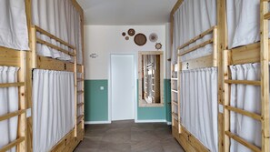 Um corredor com beliches, uma porta e decorações nas paredes.