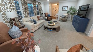 Uma sala de estar com sofá, poltronas, mesa de centro e televisão.
