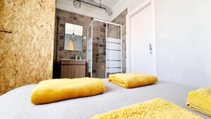 Quarto de hotel com cama, banheiro com chuveiro e espelho.