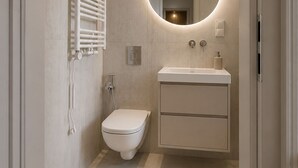 Uma casa de banho moderna com sanita, lavatório e espelho.