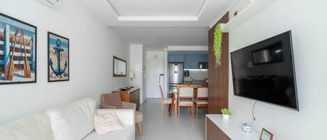 Uma sala de estar moderna com um sofá branco, uma televisão de tela plana e obras de arte nas paredes.