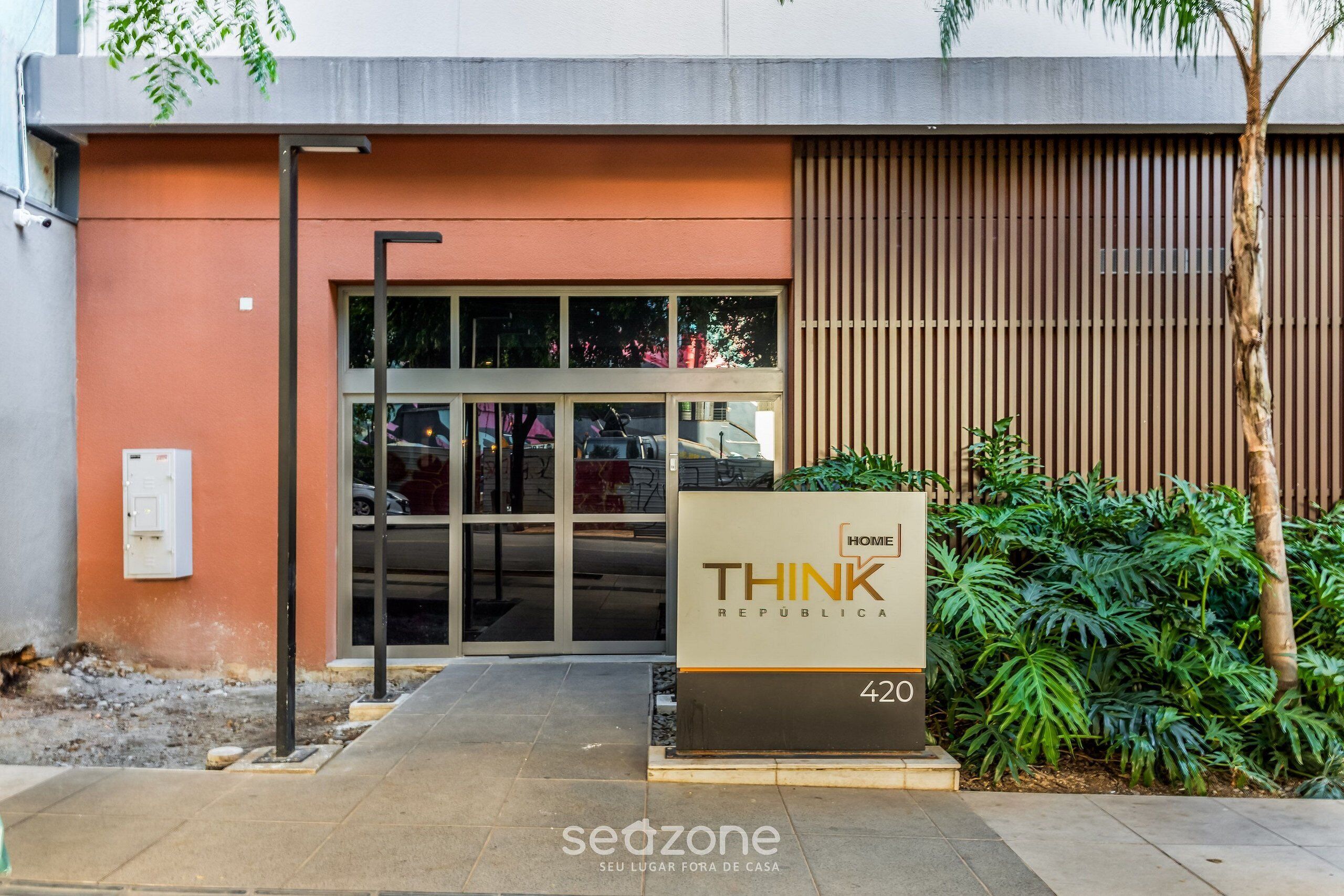 Entrada de um edifício moderno com uma placa que diz "THINK REPUBLICA 420".