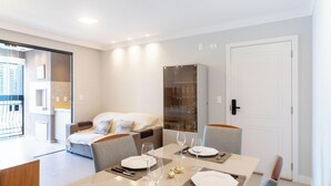 Quarto de hotel moderno com área de refeições, uma cama e um armário de vidro.