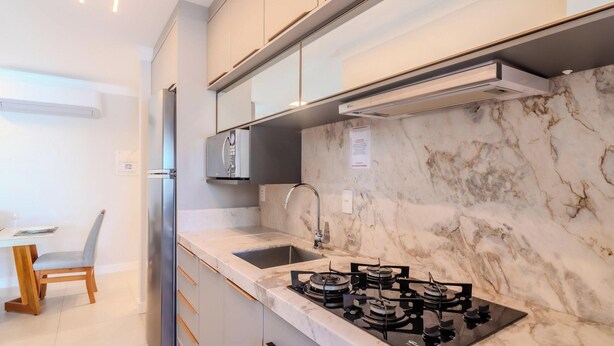 Uma cozinha moderna com fogão a gás, painel de fundo de mármore e eletrodomésticos de aço inoxidável.