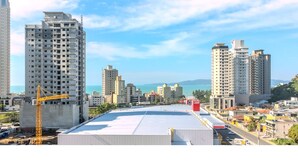Um edifício alto com uma grua de construção, céu limpo e vista distante do mar.