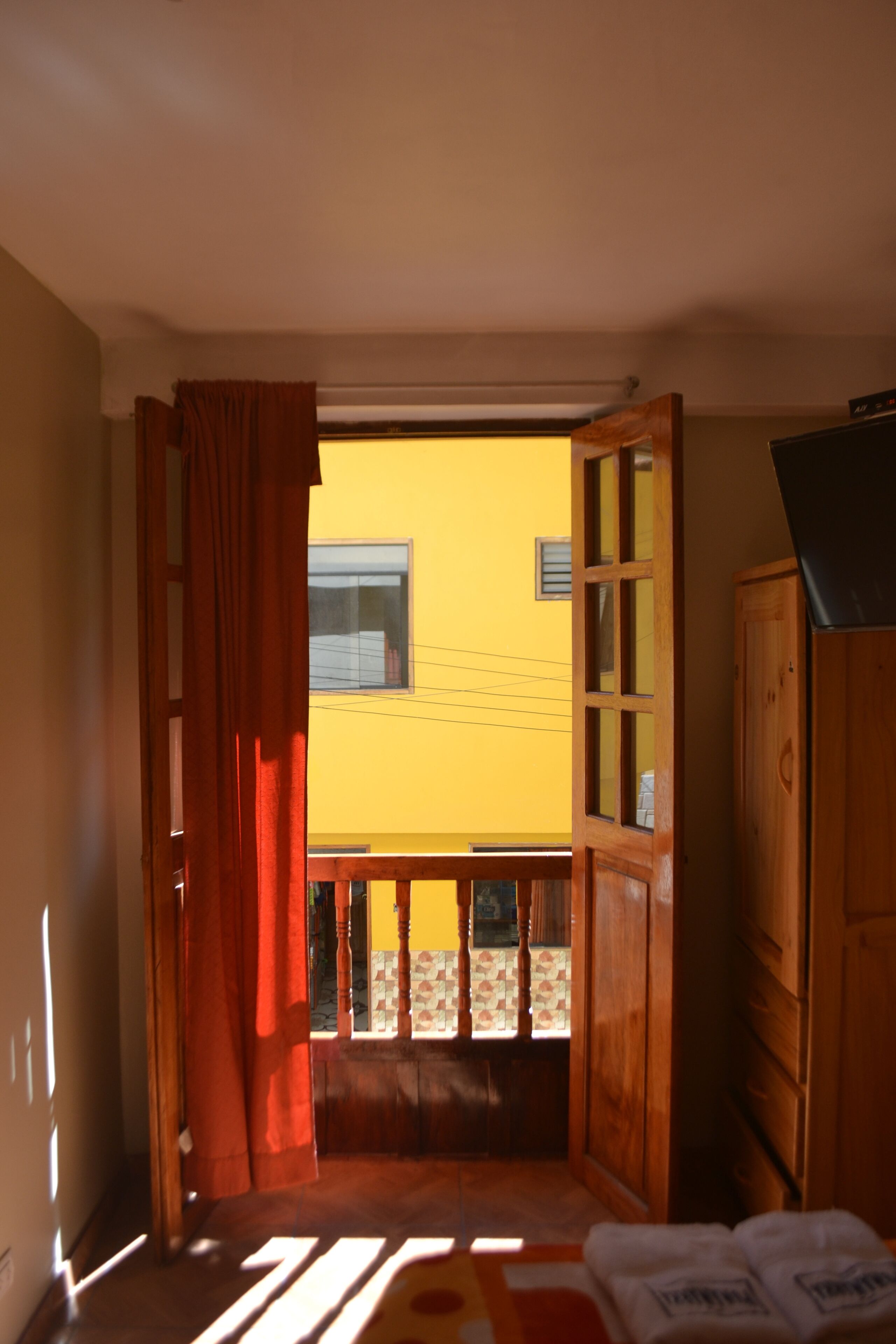 Quarto com cama, guarda-roupa de madeira e janela com cortinas.