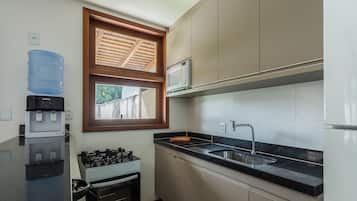 Cozinha compacta com um bebedouro, fogão, micro-ondas e pia.