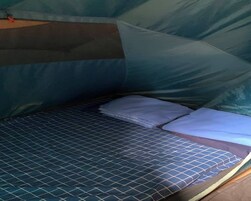 Uma tenda com uma cama interna, com um colchão e travesseiros estampados em padrão quadriculado.
