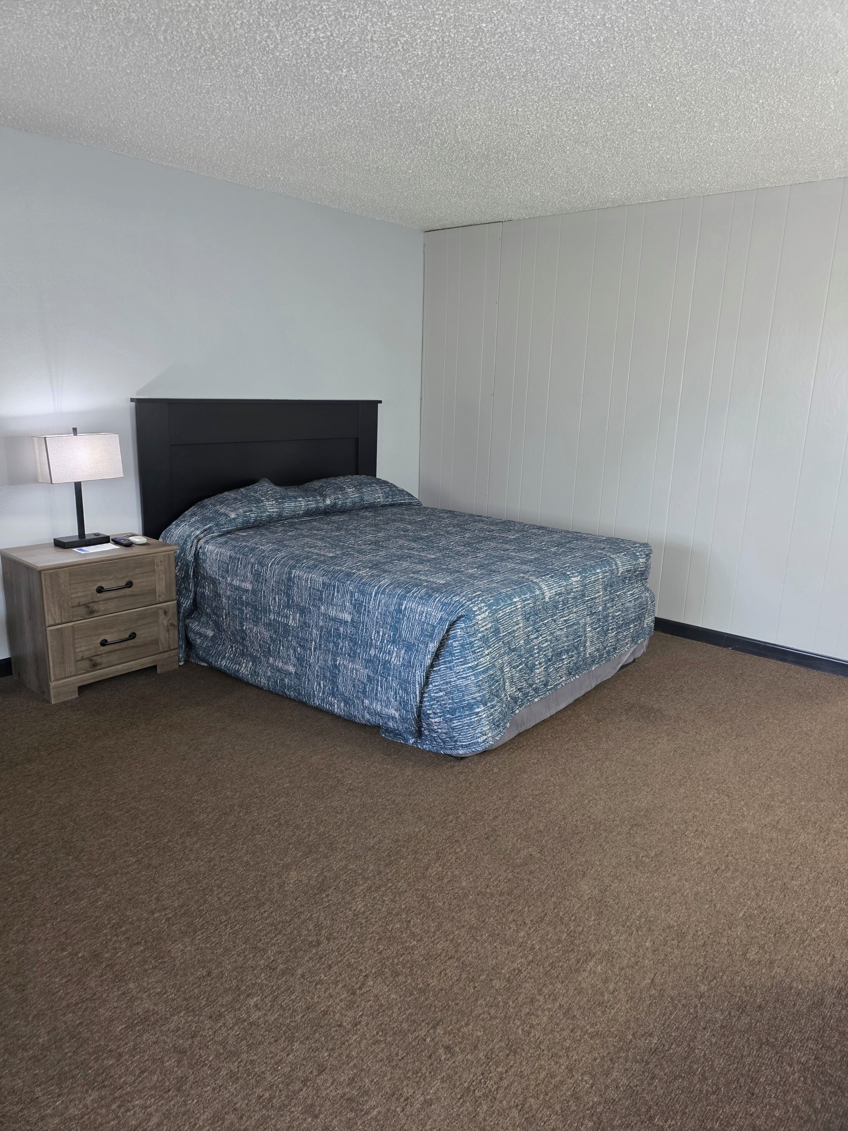 Um quarto com uma cama, uma mesa de cabeceira, uma luminária e um armário.