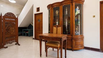 Uma área de refeições com mesa e cadeiras de madeira, um armário com portas de vidro e um painel decorativo de madeira.