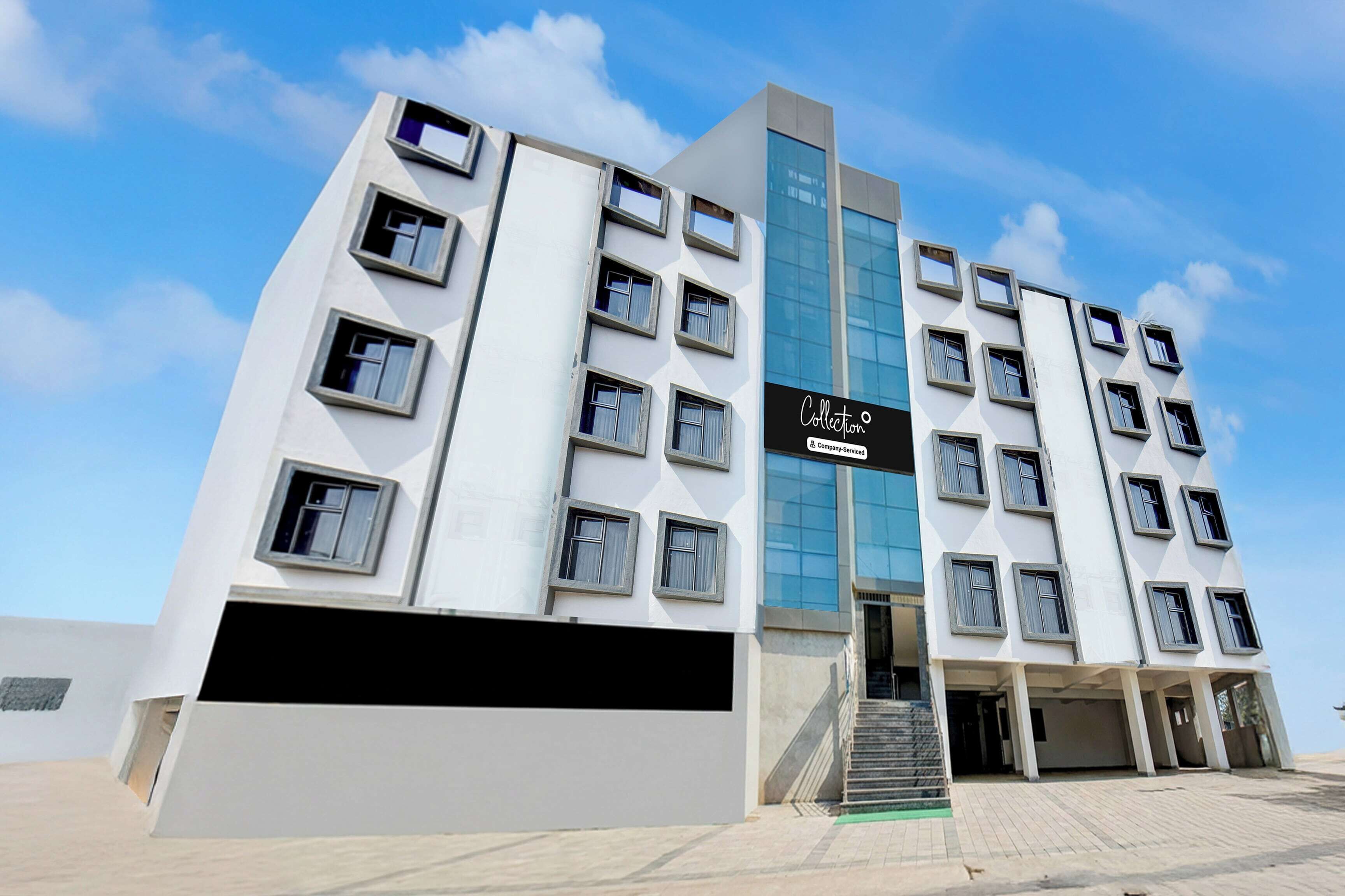 Um edifício moderno de vários andares com uma escadaria imponente que leva à entrada.