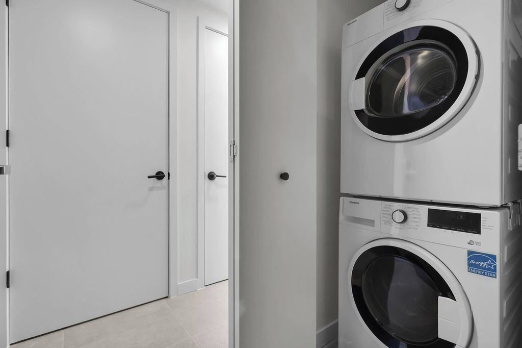 Uma lavanderia com máquinas de lavar empilhadas e uma porta fechada.