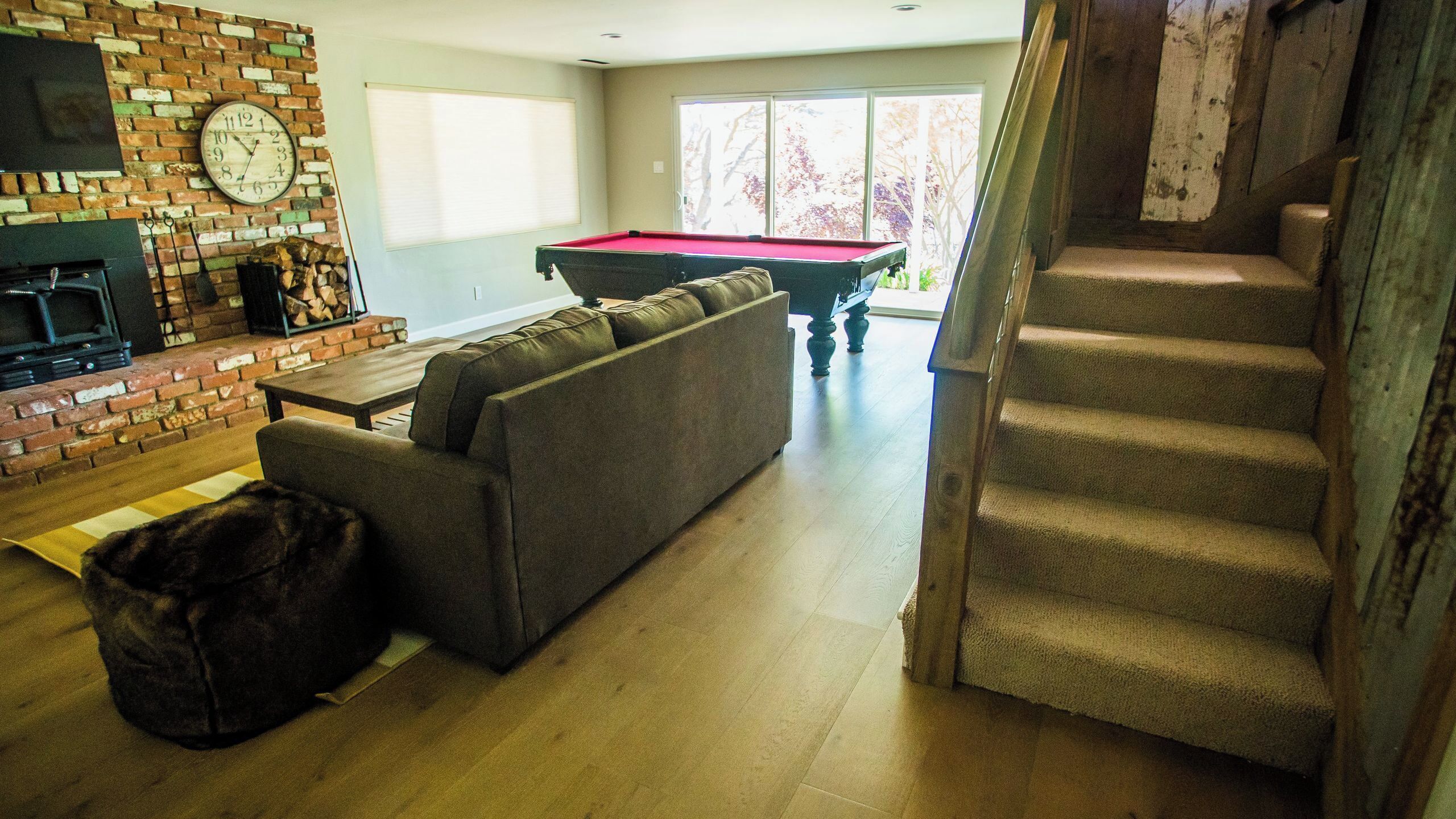 Uma sala de estar com mesa de bilhar, sofá, lareira e escada.
