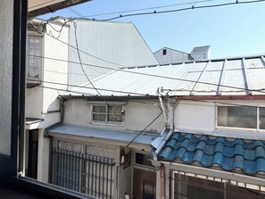 Um edifício residencial com telhado de metal corrugado, fiação elétrica aparente e entrada com portão.