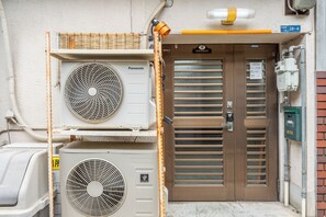 Um aparelho de ar condicionado, uma porta com uma placa e uma caixa de eletricidade.