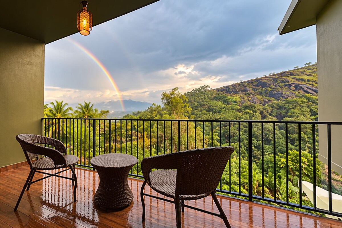 Varanda com mobiliário de vime e vista para uma paisagem exuberante com um arco-íris.