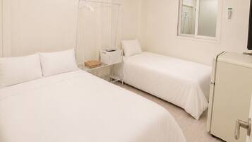 Quarto de hotel com duas camas, mesa de cabeceira, guarda-roupa e luminária no teto.