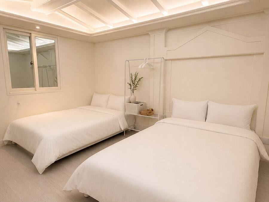 Quarto de hotel com duas camas, uma janela e um claraboia.