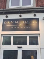 Placa de hotel com o nome 'DAMM HOTEL' e a localização 'FREDERIKSHAVN'.