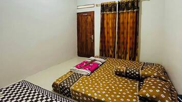 Um quarto com uma cama, uma janela com cortinas, uma porta e uma luminária no teto.