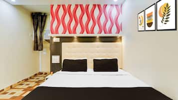 Quarto de hotel com uma cama grande, parede com padrão vermelho e obras de arte emolduradas.