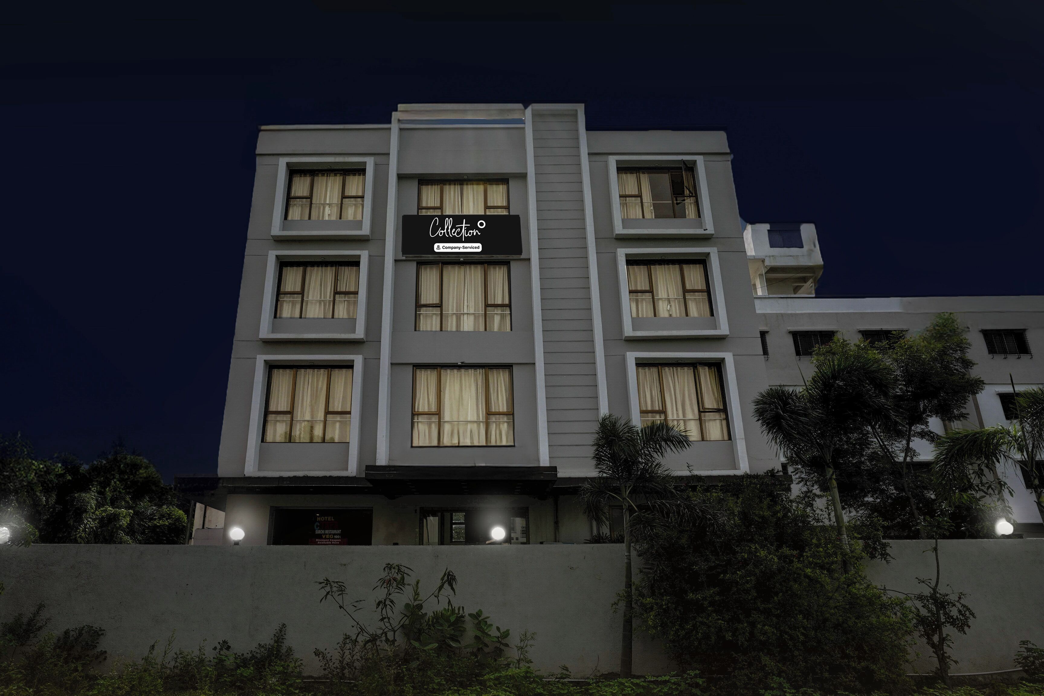 Um hotel de vários andares com fachada moderna, grandes janelas e uma placa indicando ser um empreendimento de serviços empresariais.
