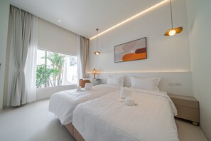 Quarto de hotel moderno com duas camas, uma janela grande com cortinas, mesa de cabeceira com abajur e uma obra de arte pendurada na parede.