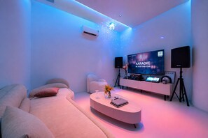 Uma sala de estar moderna com televisão de tela plana, alto-falantes, um sofá e uma mesa de centro.