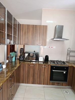 Uma cozinha moderna com armários de madeira, coifa de aço inoxidável, micro-ondas embutido e lava-louças.