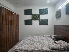 Quarto com cama, guarda-roupa e parede com padrão geométrico.