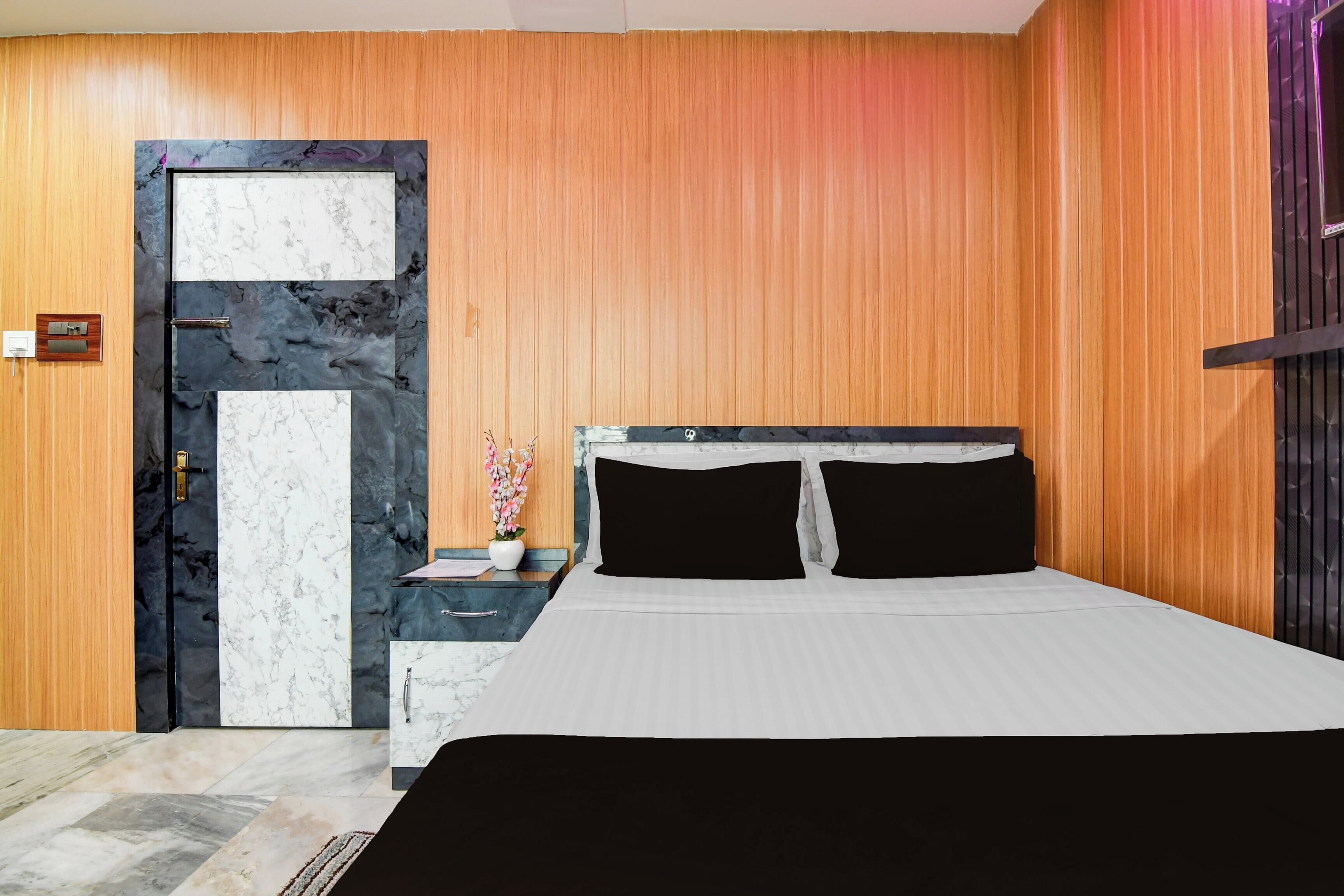 Quarto com cama, mesa de cabeceira, porta e parede com painel de madeira.