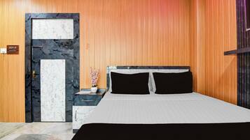 Quarto com cama, mesa de cabeceira, porta e parede com painel de madeira.